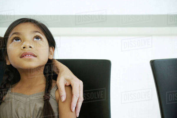 Little girl with woman's hand on her shoulder, looking up, close-up ...