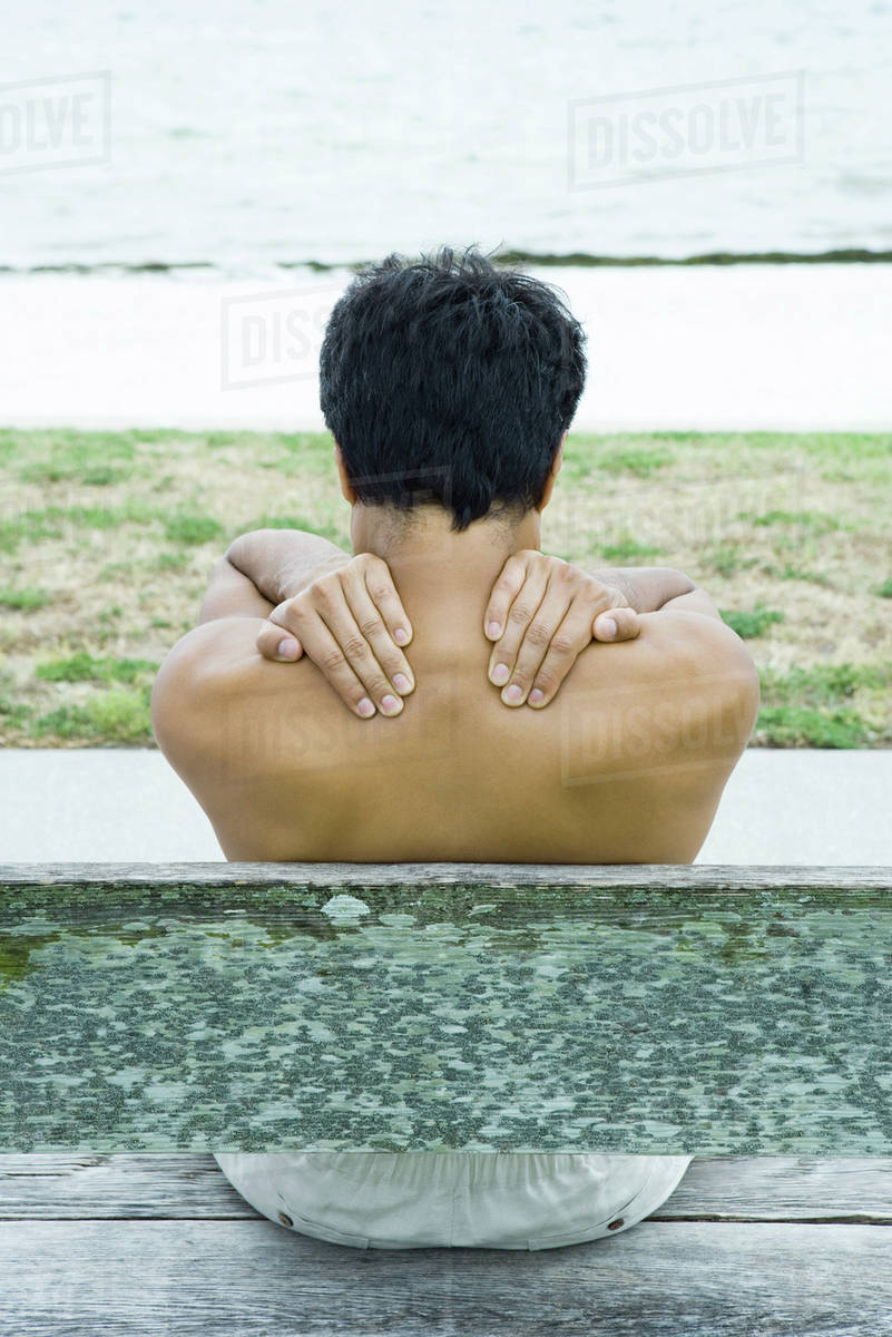 Man sitting on bench, hands on shoulders, rear view - Stock Photo ...