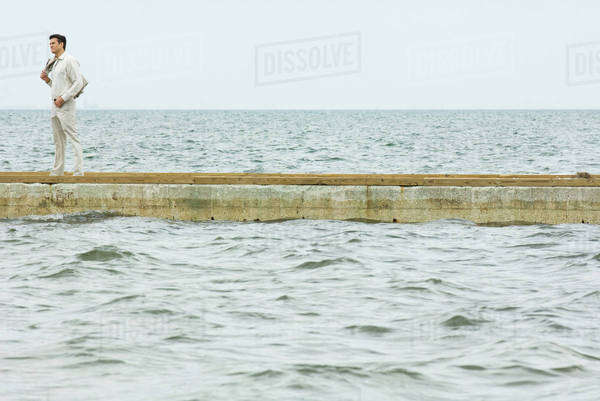Man standing on jetty, looking at sea, in mid distance - Stock Photo ...
