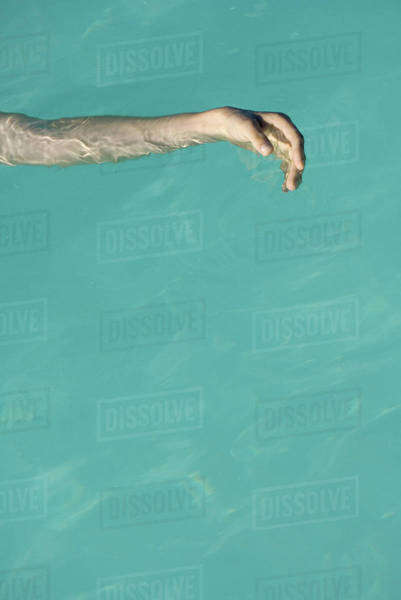 Woman's arm floating in pool - Stock Photo - Dissolve