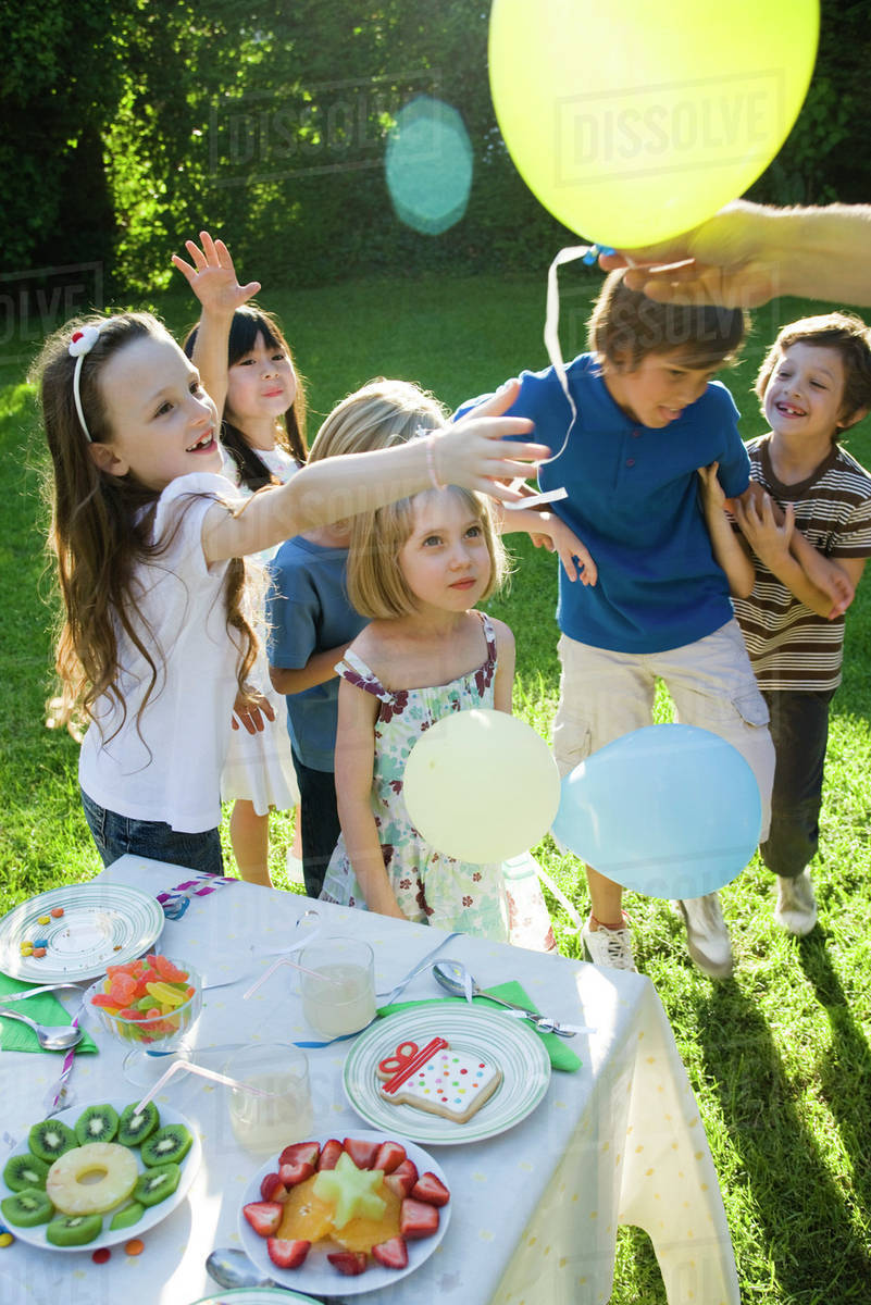 Handing out balloons at children's birthday party - Stock Photo - Dissolve