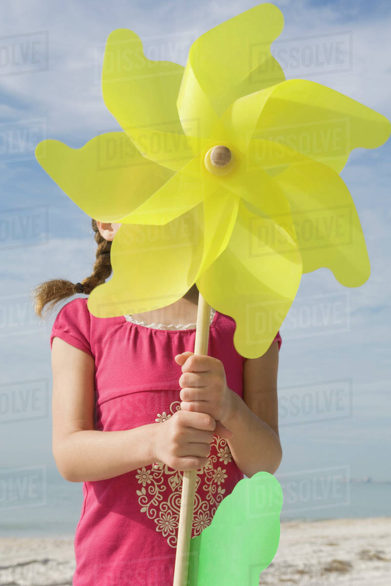 Girl standing behind large pinwheel - Royalty-free Stock Photo | Dissolve