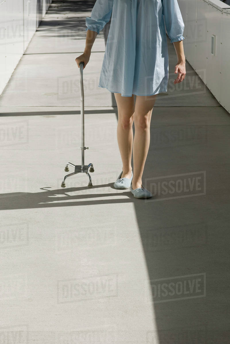Recovering patient using cane to walk outdoors - Stock Photo - Dissolve