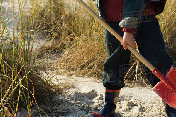 Boy digging with shovel in sand - Stock Photo - Dissolve