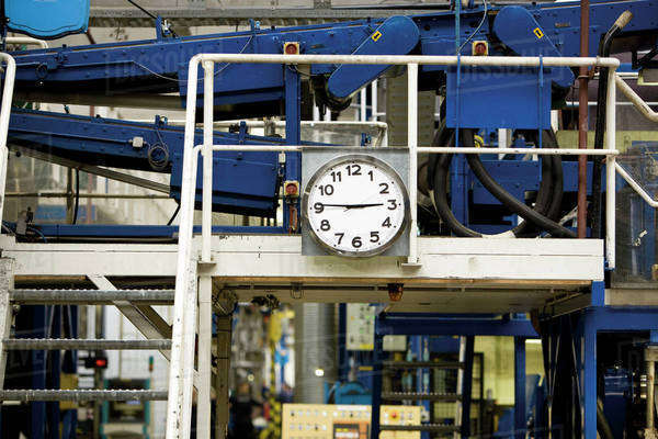 Clock mounted beside metal stairs in carpet tile factory - Stock Photo ...