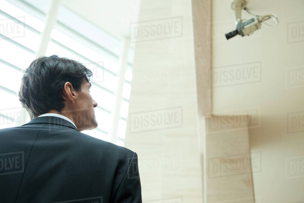 Businessman looking up at security camera - Royalty-free Stock Photo ...