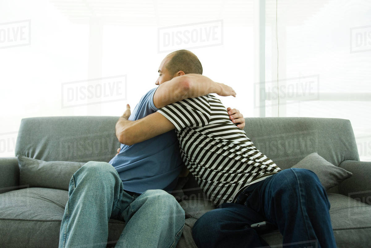 Two men embracing on sofa - Royalty-free Stock Photo | Dissolve