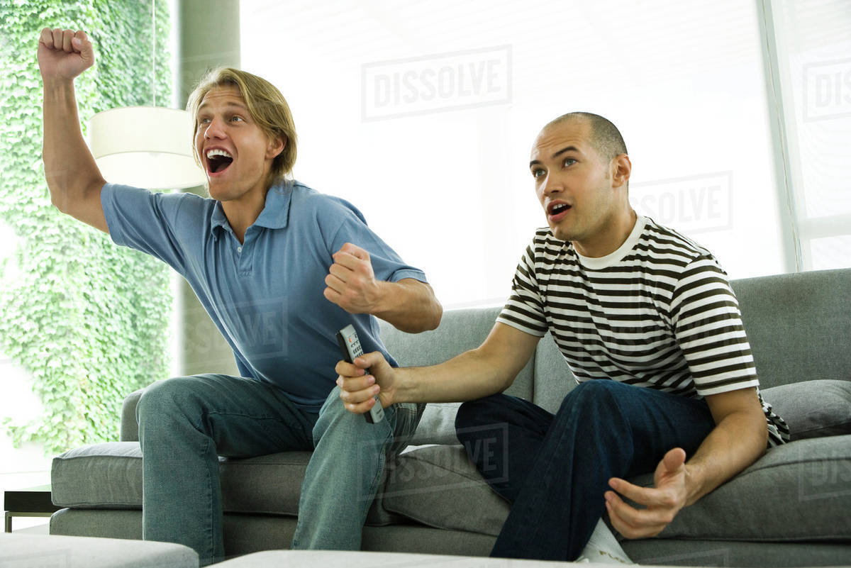 Two men watching TV and cheering on sofa - Royalty-free Stock Photo ...