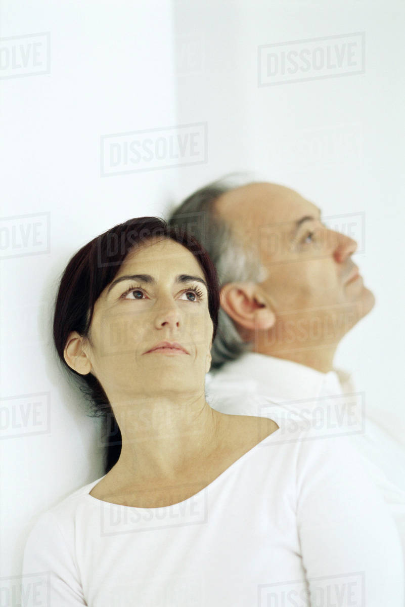 Man and woman sitting, leaning against each other looking away ...