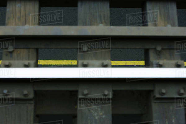 Rails, wooden girders of elevated railway, yellow lines of street below ...