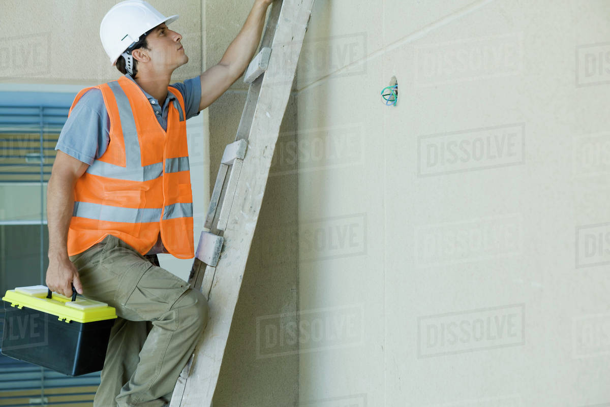 Man climbing ladder carrying toolbox - Stock Photo - Dissolve