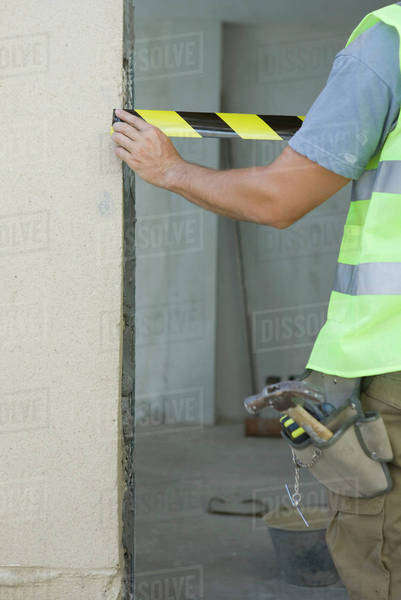 Worker placing safety tape barricading area - Stock Photo - Dissolve