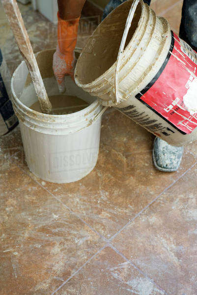 Worker pouring plaster from one bucket to another - Stock Photo - Dissolve