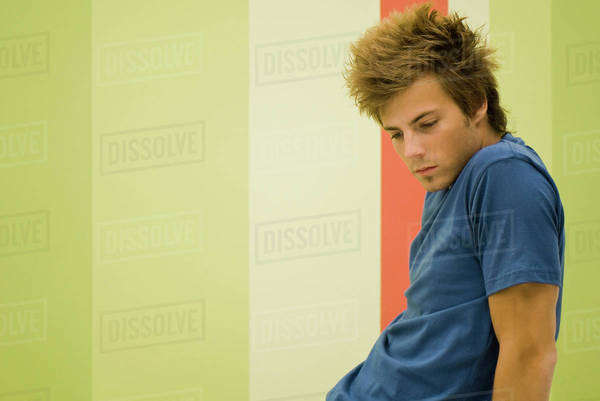 Young man looking down in thought - Stock Photo - Dissolve