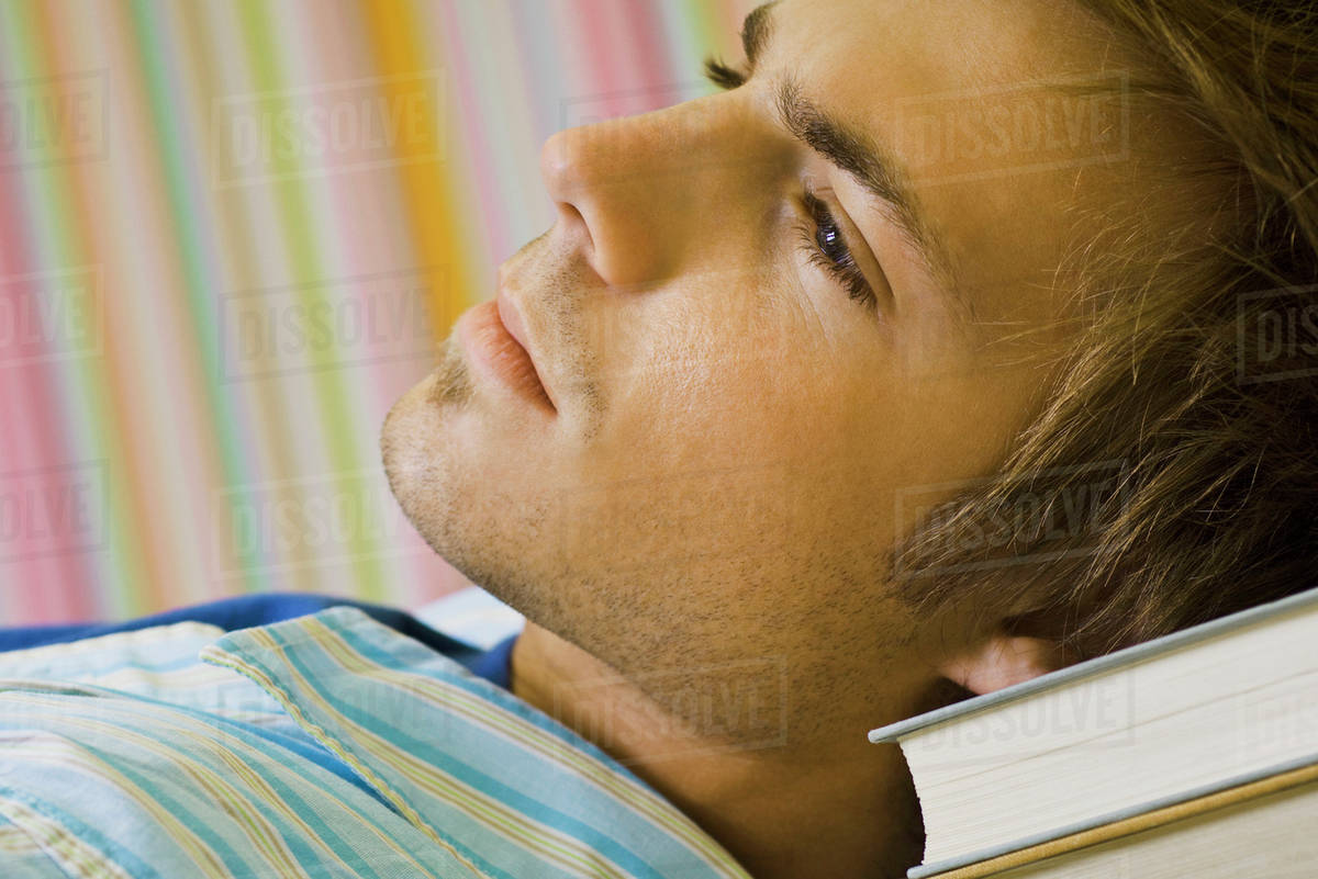 Young man daydreaming, resting head on stack of books - Stock Photo ...