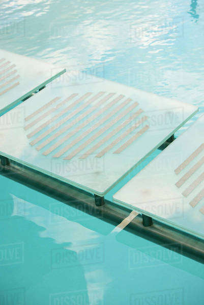 Stepping stones leading across swimming pool - Stock Photo - Dissolve