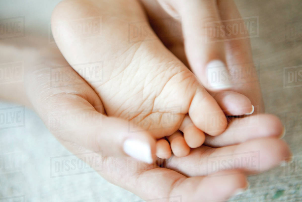 Woman's hands holding baby's foot - Royalty-free Stock Photo | Dissolve