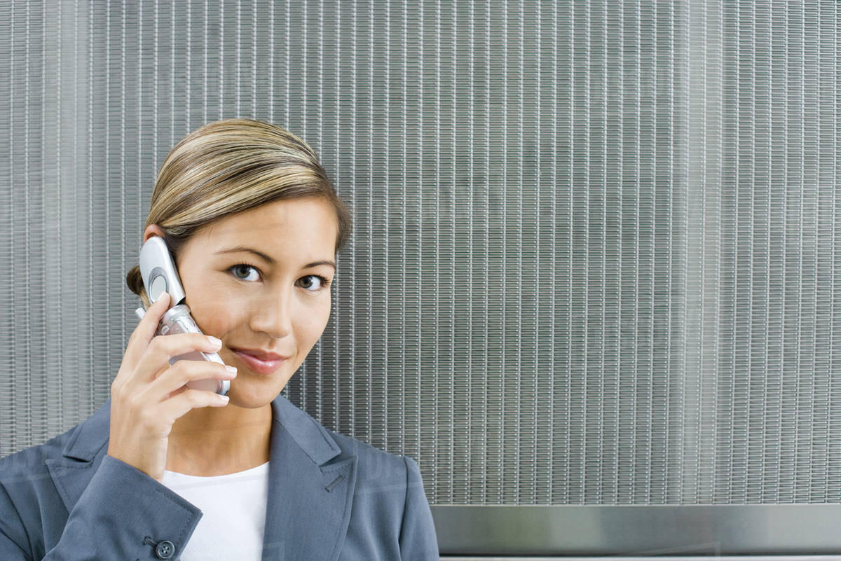 Woman using cell phone, smiling at camera - Royalty-free Stock Photo ...