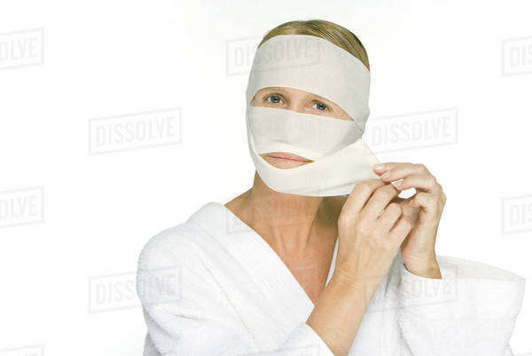 Woman removing bandages from face, looking at camera - Royalty-free ...