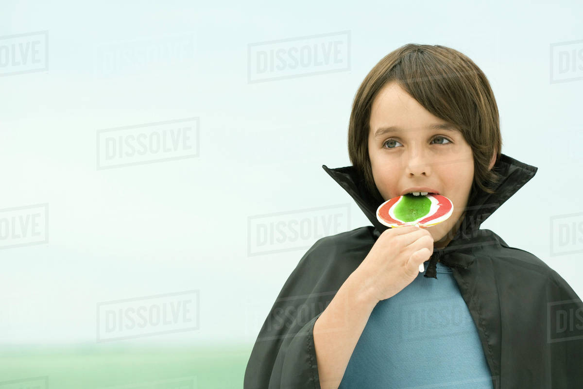 Boy wearing vampire cape, eating large lollipop, portrait - Royalty ...