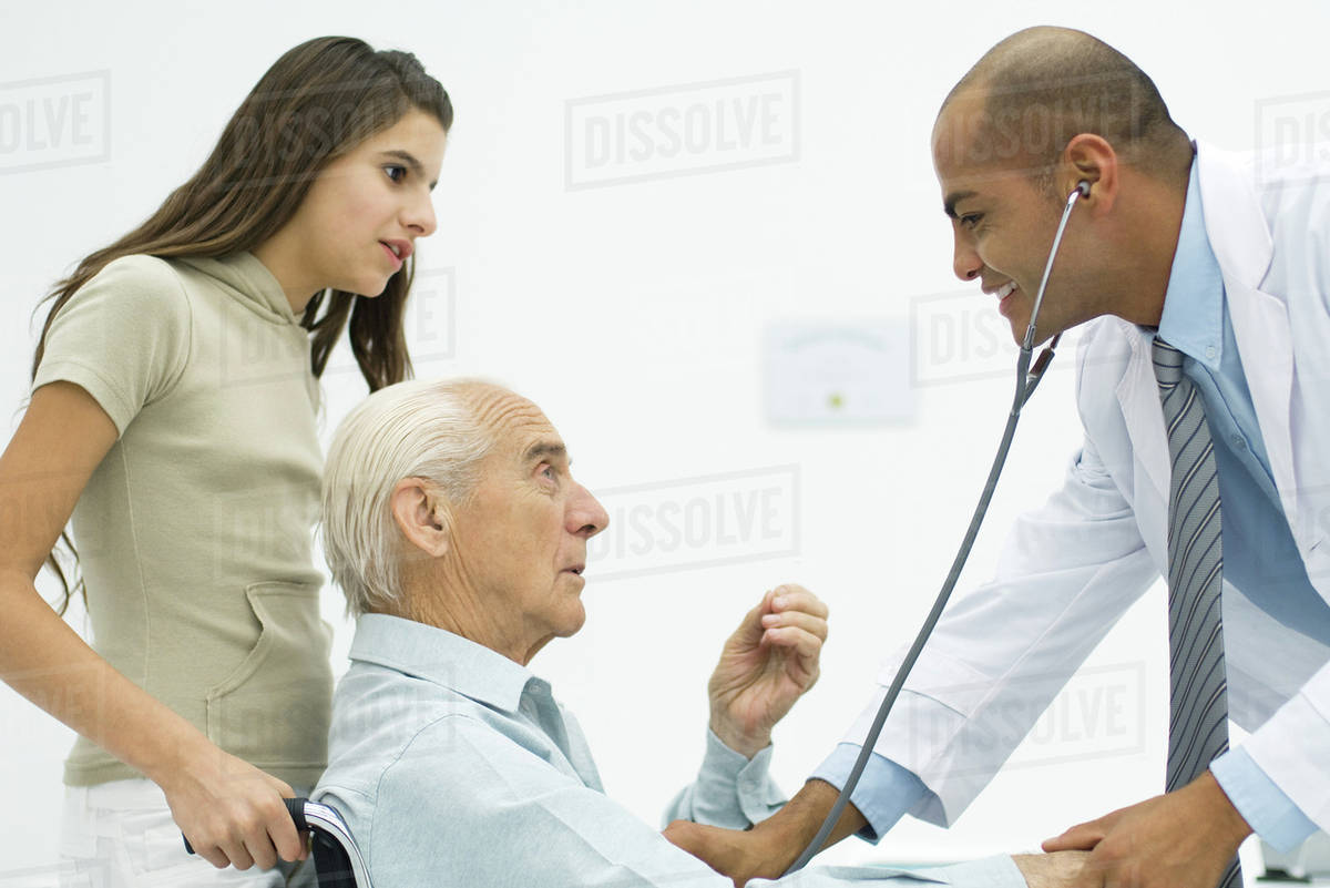 Doctor listening to senior man's heart, teen girl watching - Stock ...