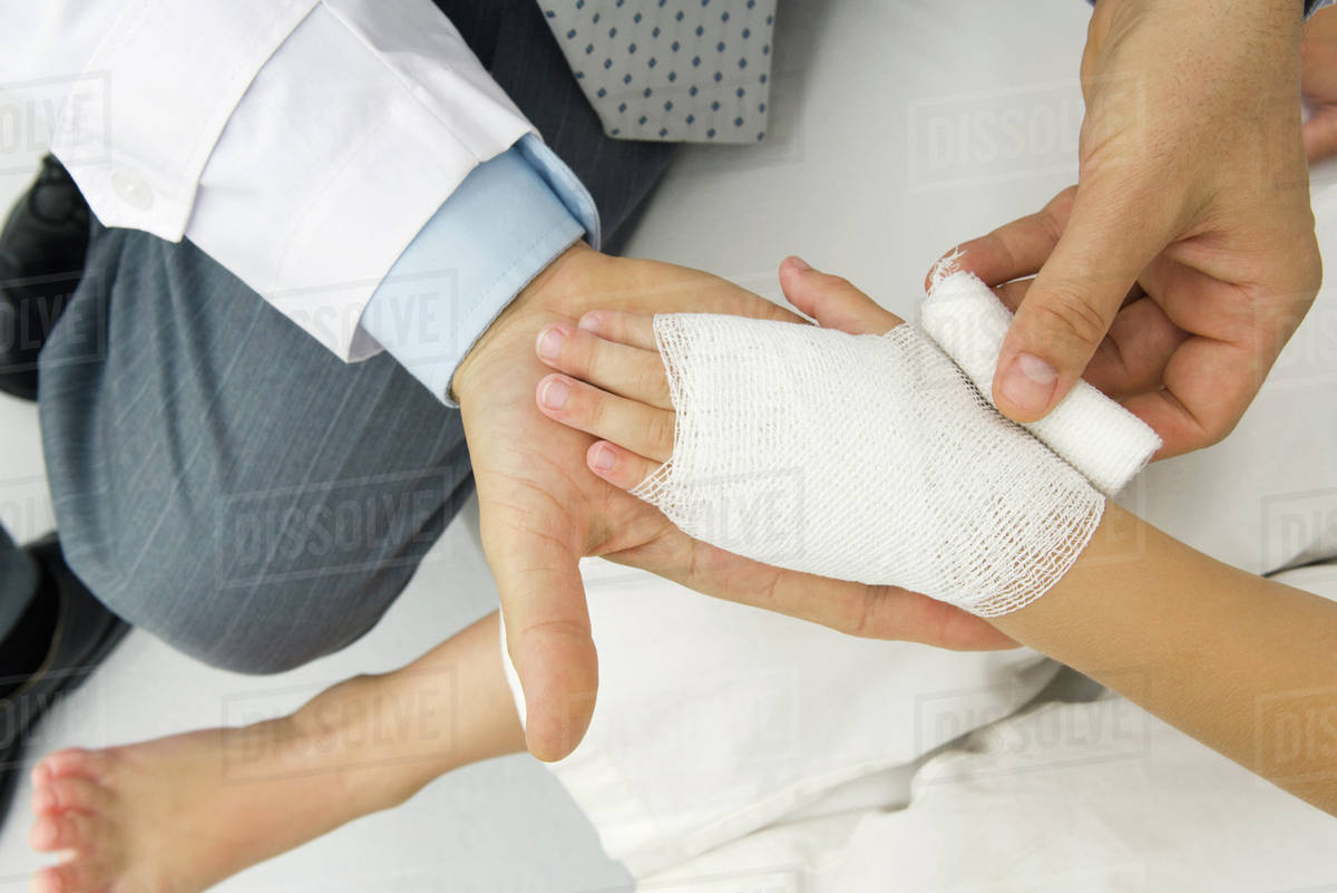 Doctor wrapping a patient's hand in gauze, high angle view - Royalty ...