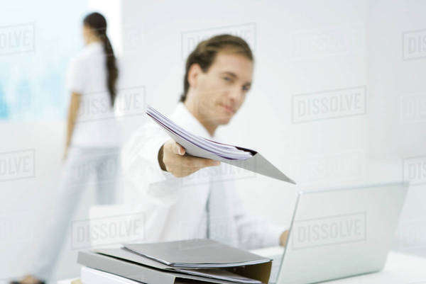 Professional man handing folder to camera, focus on foreground ...