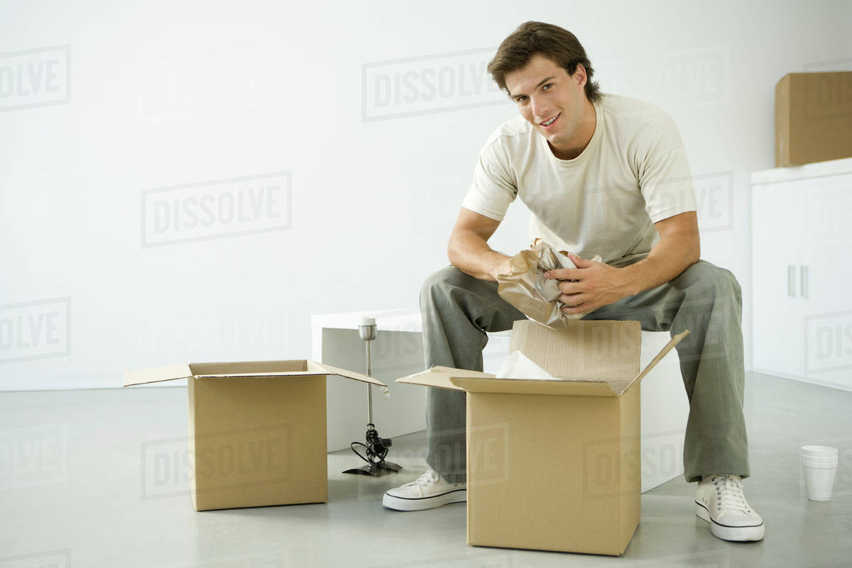 Man unpacking boxes, sitting on bench, smiling at camera - Stock Photo ...