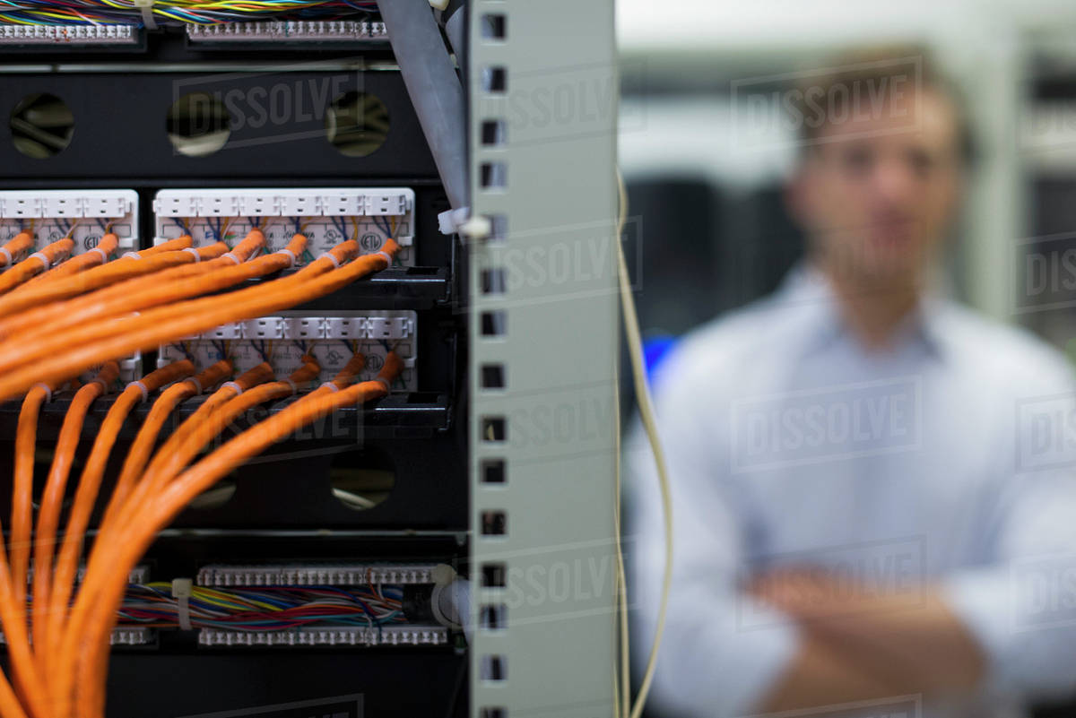 Network cables connected to computer mainframe, computer technician in ...