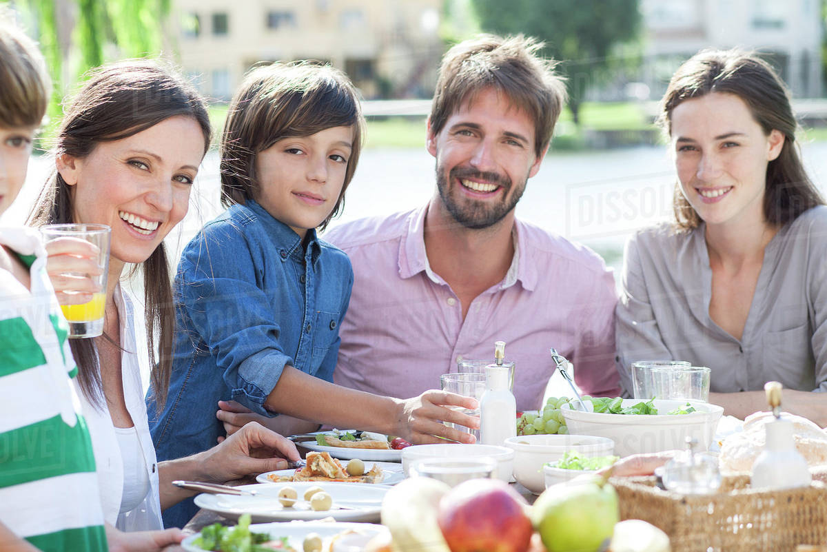 Family eating together outdoors, portrait - Stock Photo - Dissolve