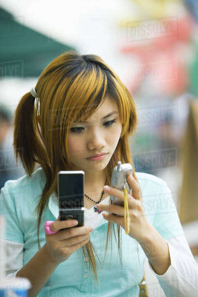 Teenage girl using two cell phones - Royalty-free Stock Photo | Dissolve