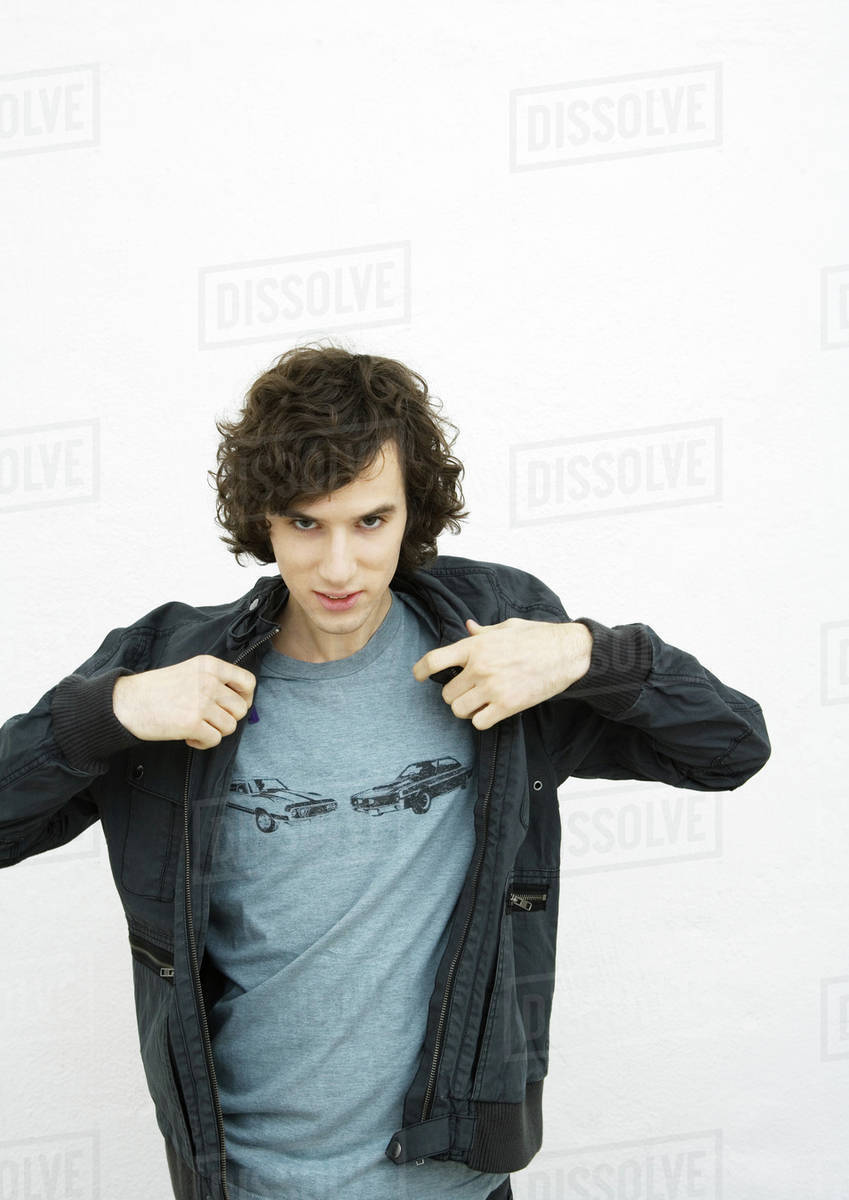 Young man putting on jacket, portrait - Royalty-free Stock Photo | Dissolve