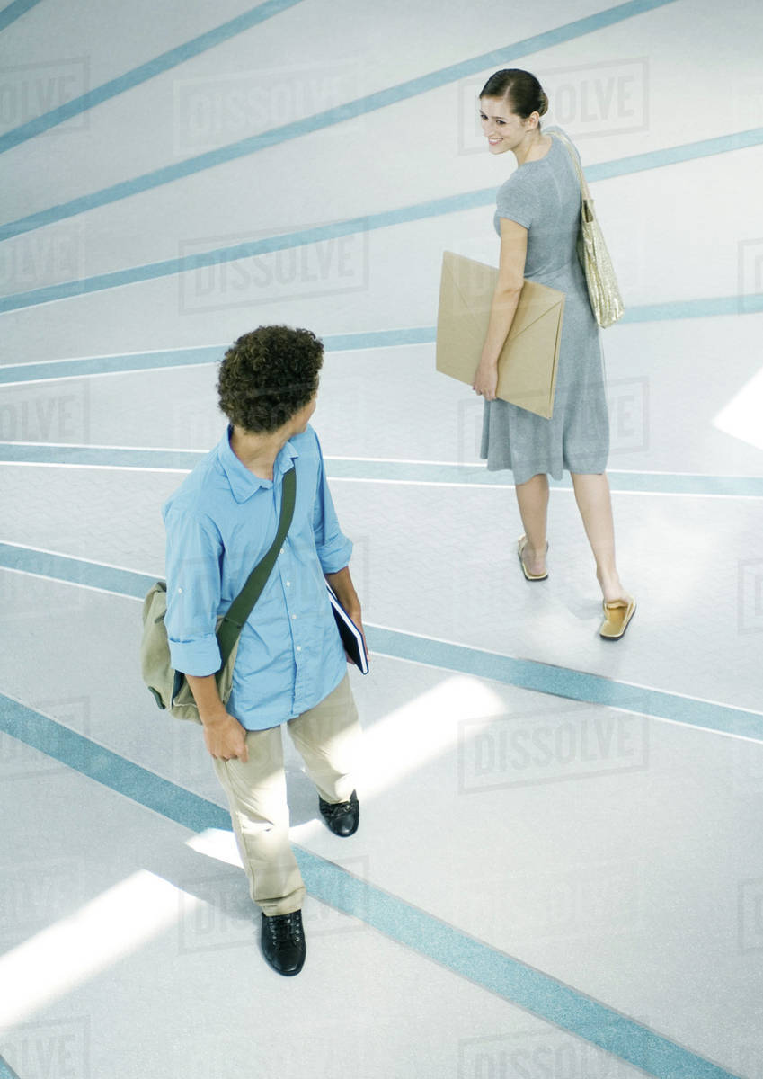 Man and woman looking over shoulders at each other in passing, full ...