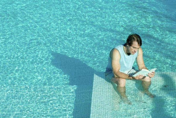 Man sitting in swimming pool, reading - Royalty-free Stock Photo | Dissolve