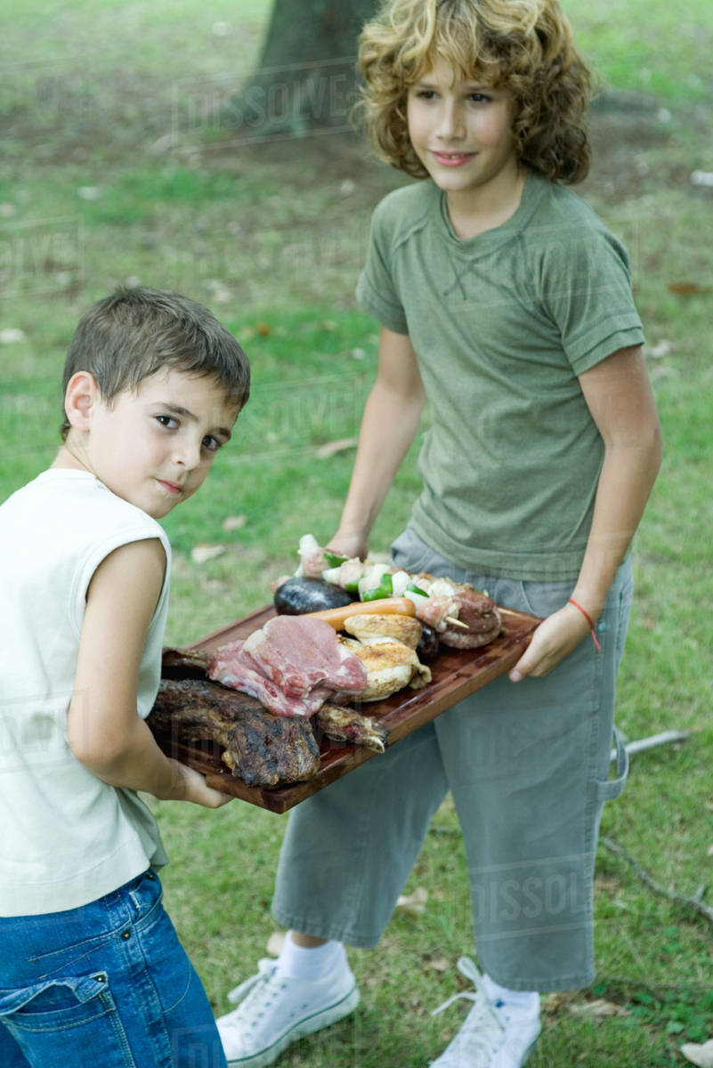 Two boys carrying tray of grilled and raw meats - Royalty-free Stock ...
