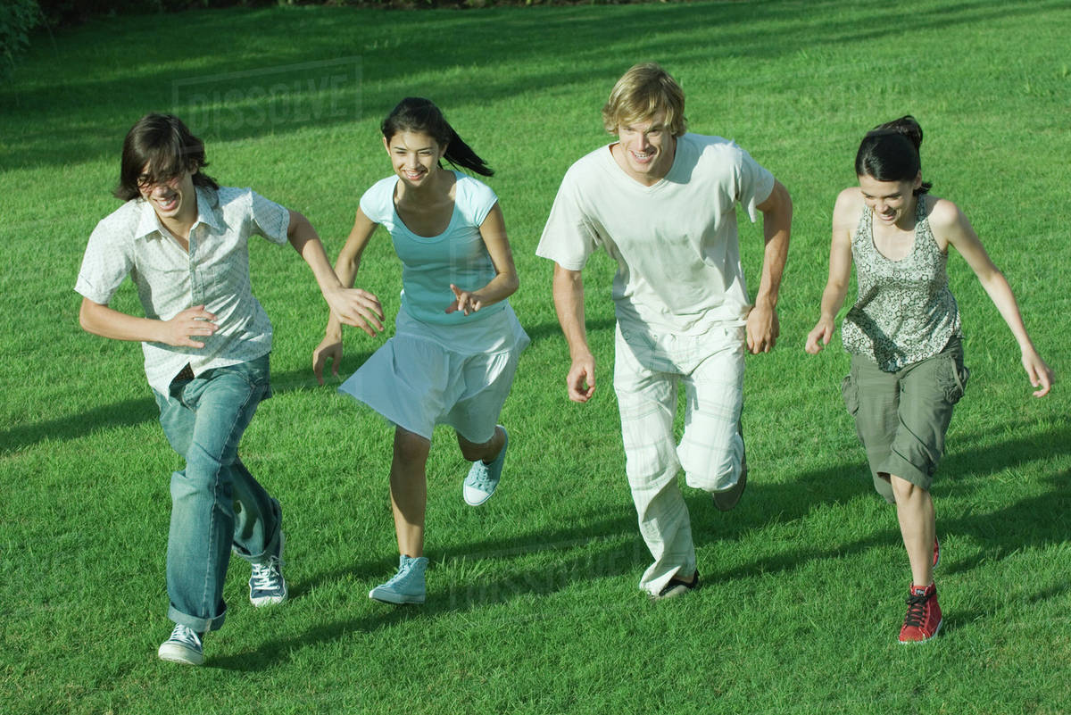 Group of young friends, running across grass together - Royalty-free ...