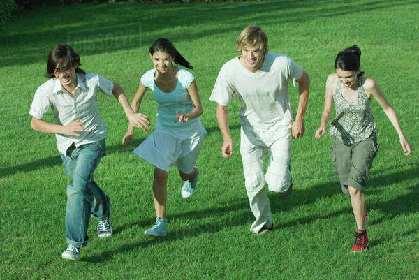 Group of young friends, running across grass together - Royalty-free ...