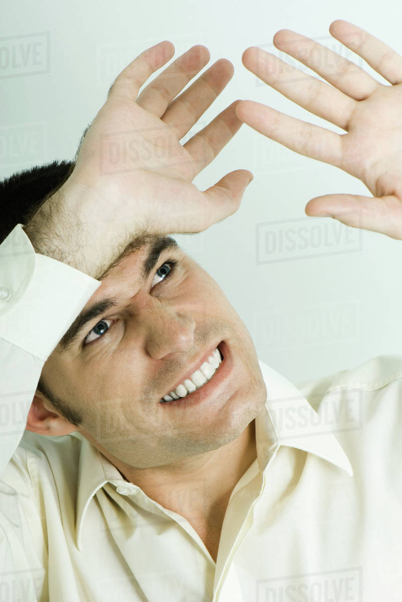 Man looking up, holding up hands protectively, head and shoulders ...