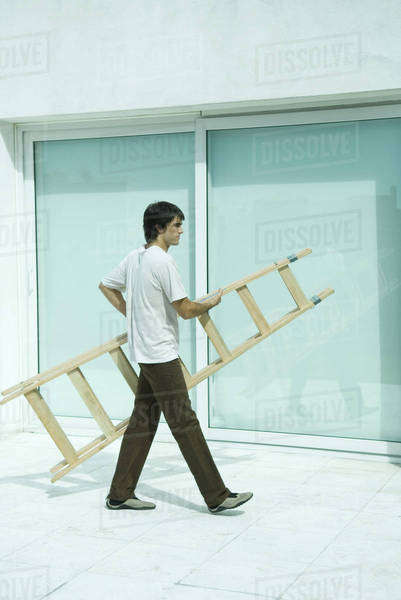 Man carrying ladder, full length - Royalty-free Stock Photo | Dissolve