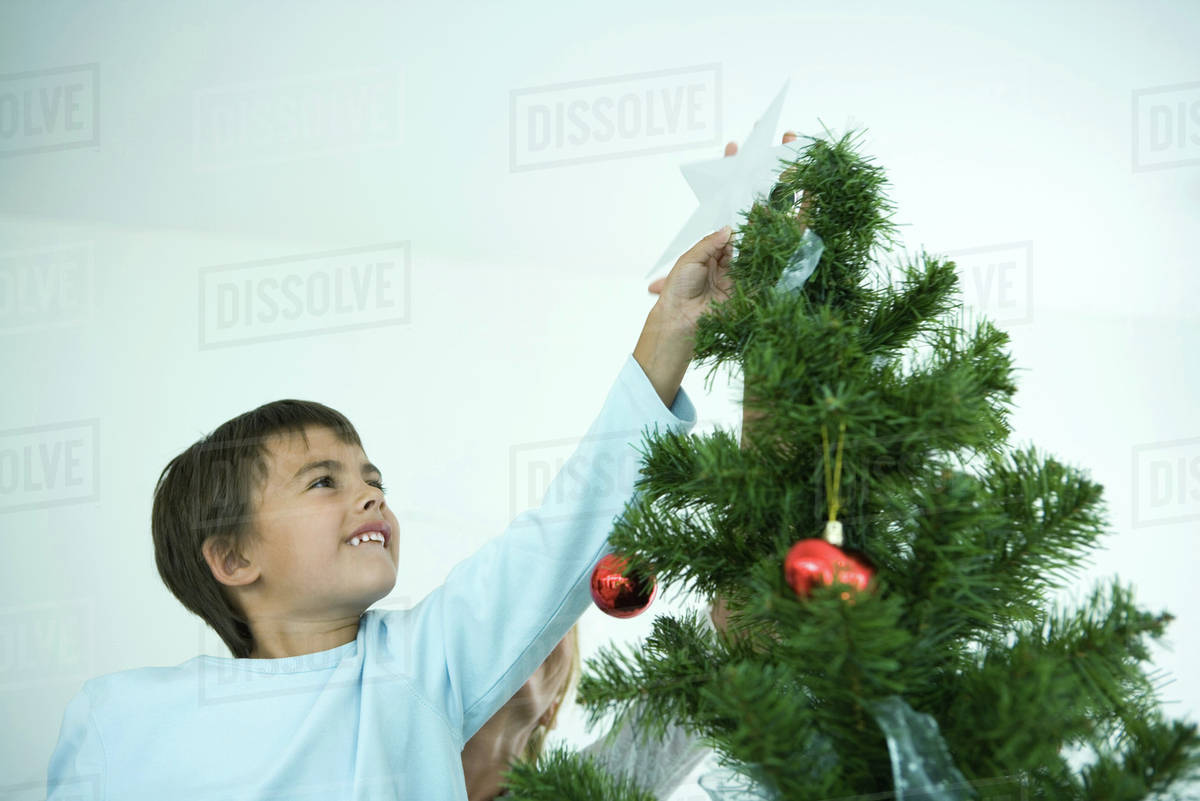 Boy putting star on top of Christmas tree - Royalty-free Stock Photo ...