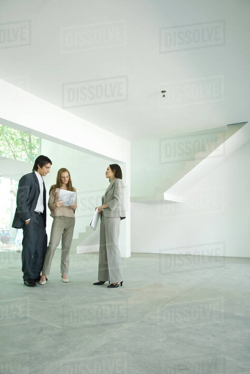 Female real estate agent standing in empty home interior with young ...