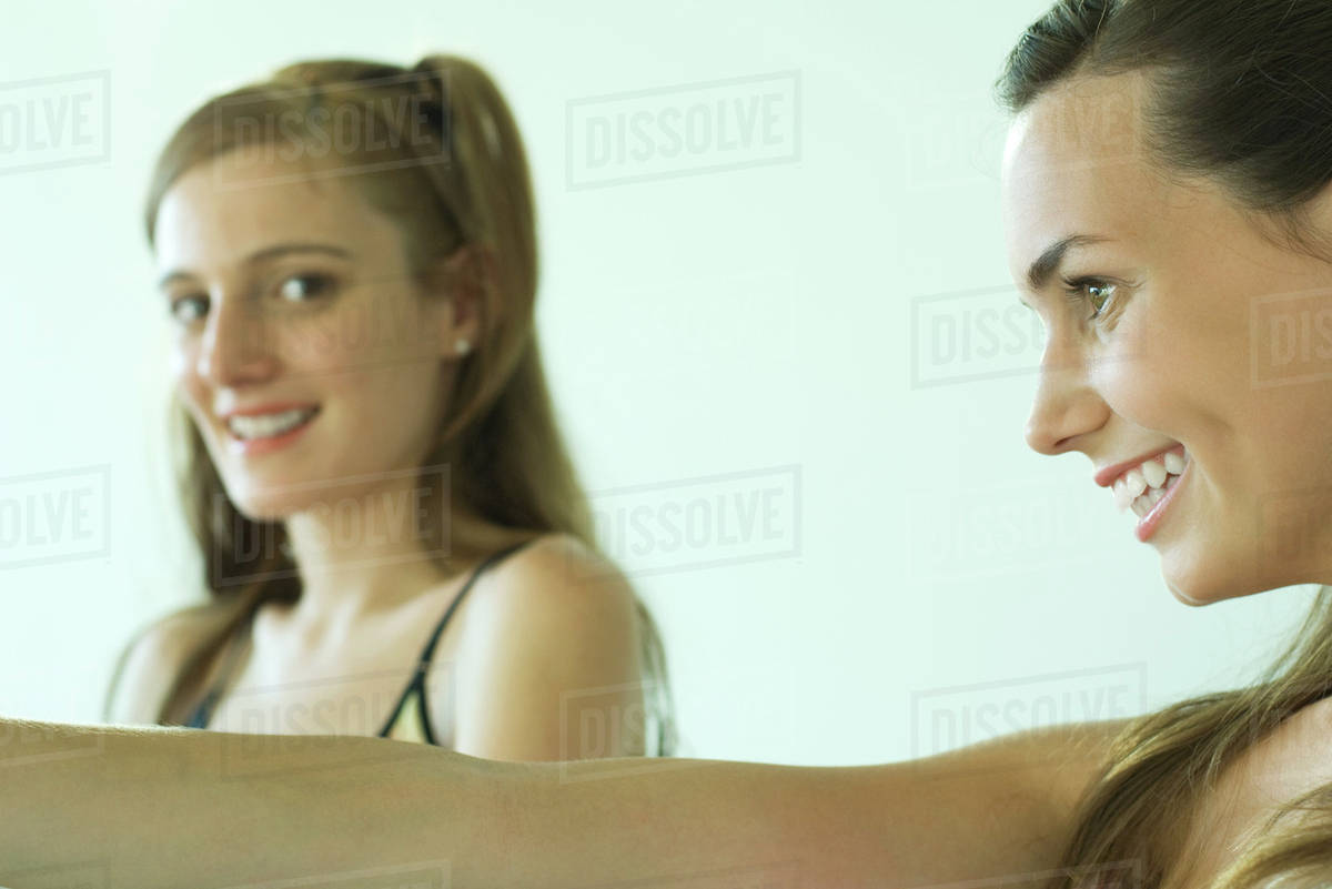 Two young friends smiling, one looking at camera, side view - Royalty ...