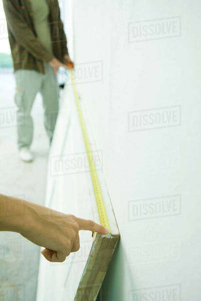 Man and woman measuring door with measuring tape, cropped view ...