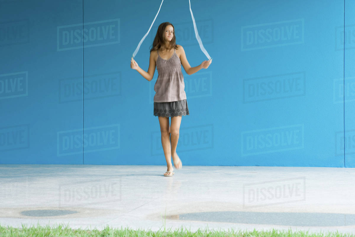 Young woman jumping rope, front view, full length - Stock Photo - Dissolve