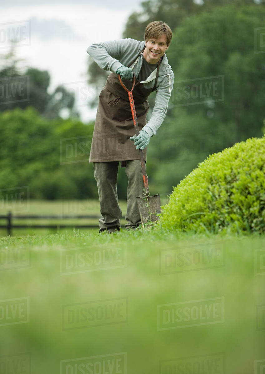 Young man digging in yard - Stock Photo - Dissolve