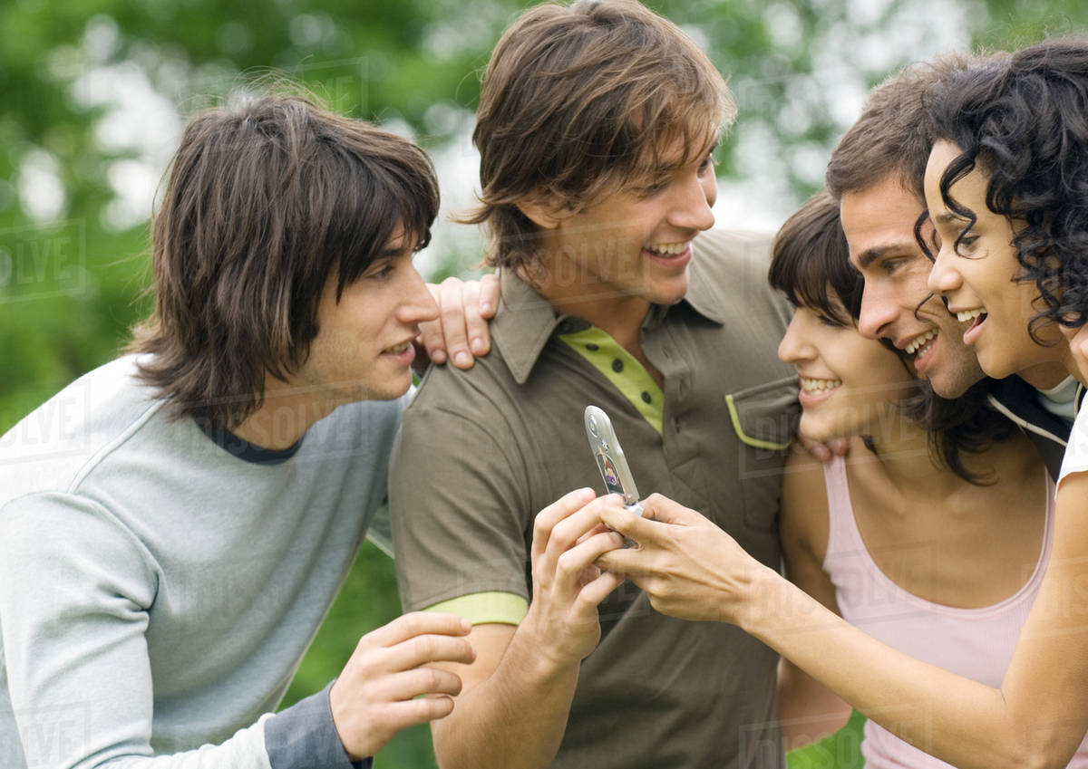 Group of young friends looking at cell phone - Royalty-free Stock Photo ...