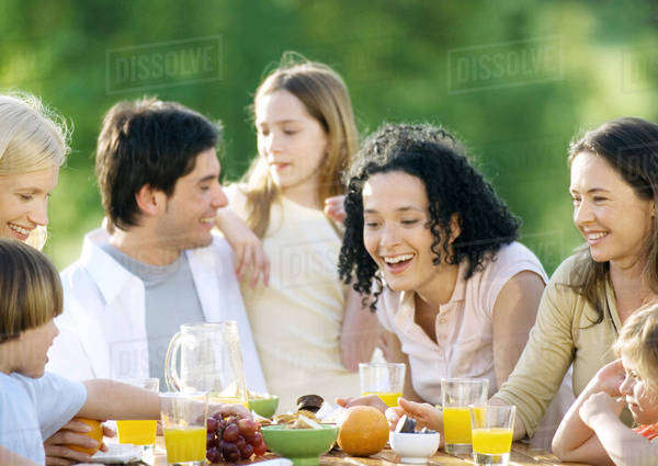 Family sitting around table outdoors - Royalty-free Stock Photo | Dissolve