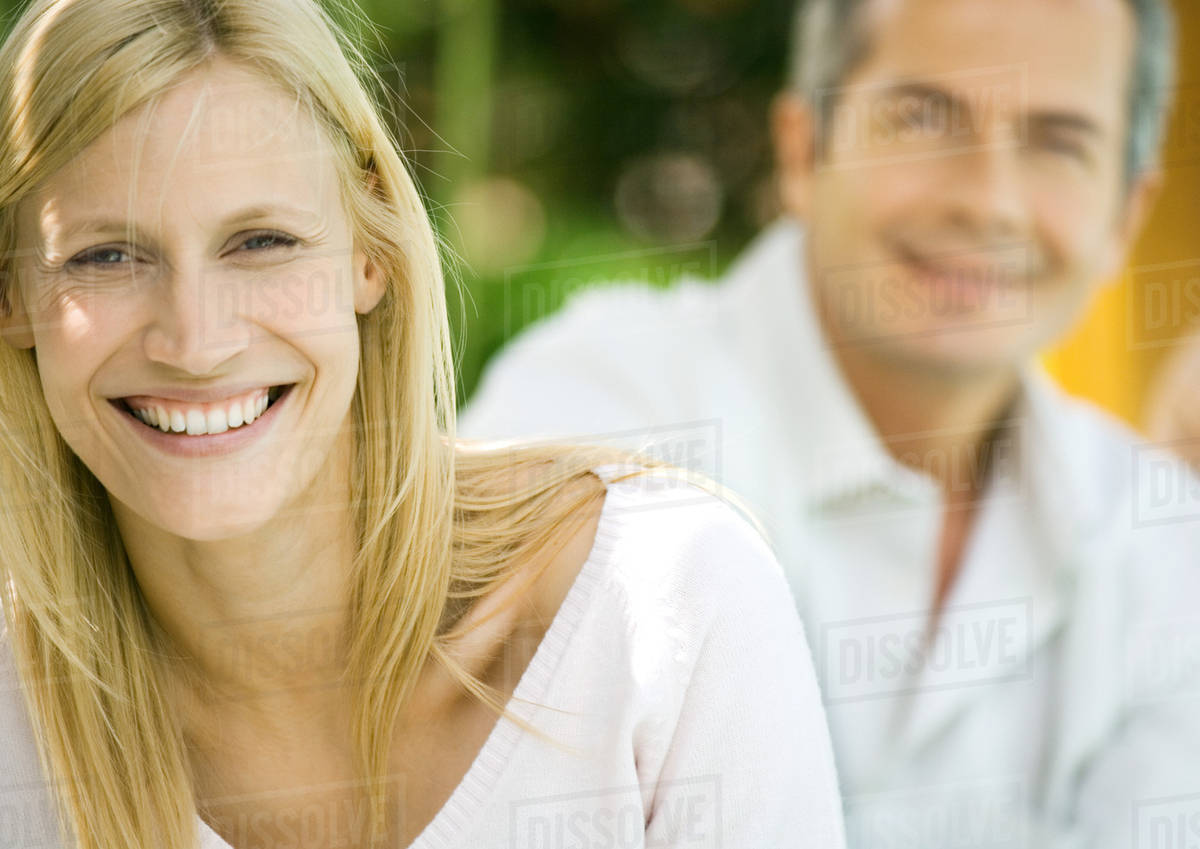 Woman smiling, man in background, portrait - Stock Photo - Dissolve