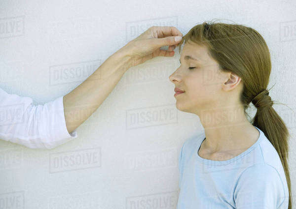 Mother touching her daughter 's forehead, closed eyes and slightly ...