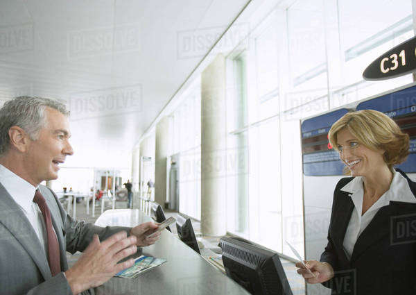 Businessman at airline check-in counter - Stock Photo - Dissolve